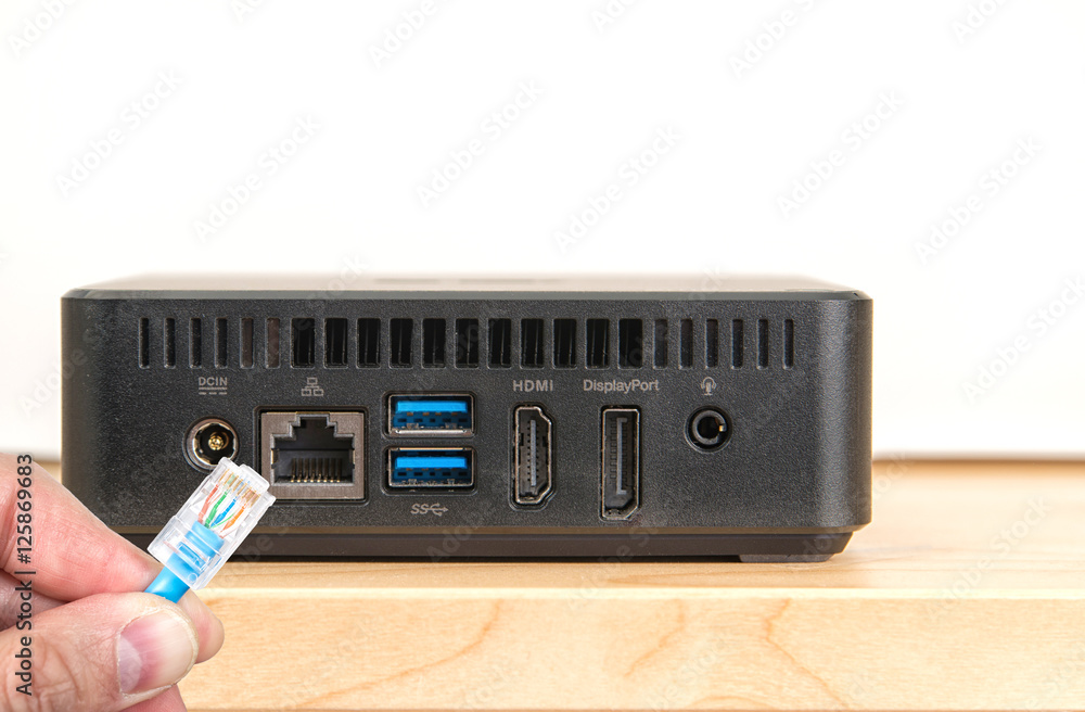 Hand connecting a network cable to back panel of micro computer Stock ...