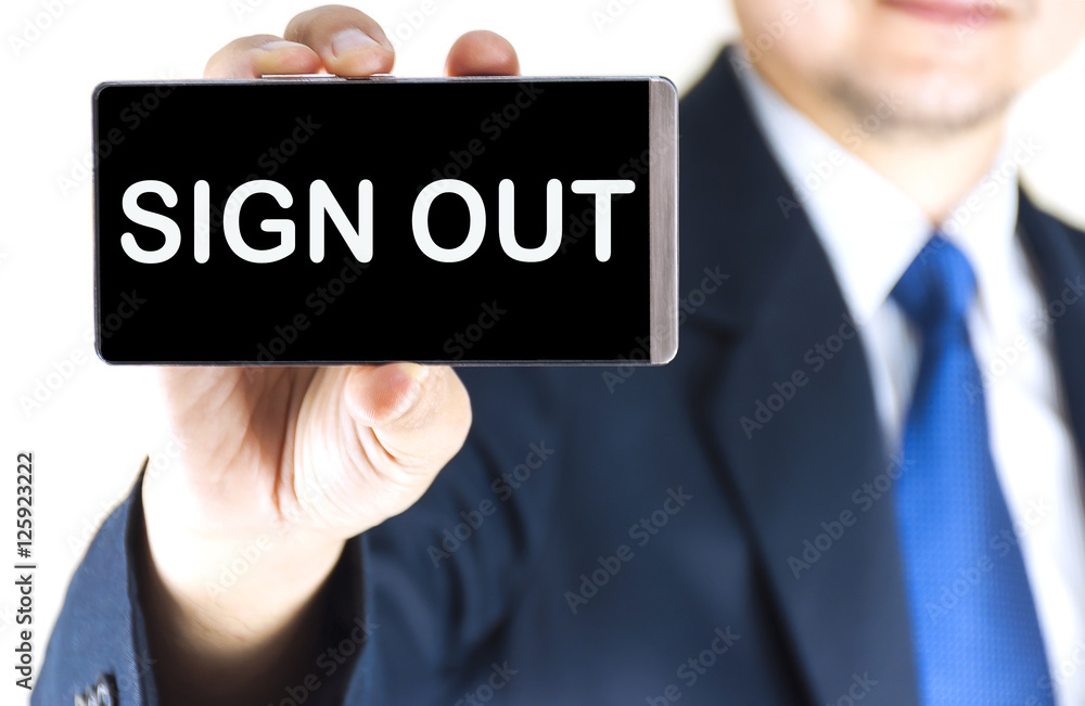 SIGN OUT word on mobile phone screen in blurred young businessman hand ...