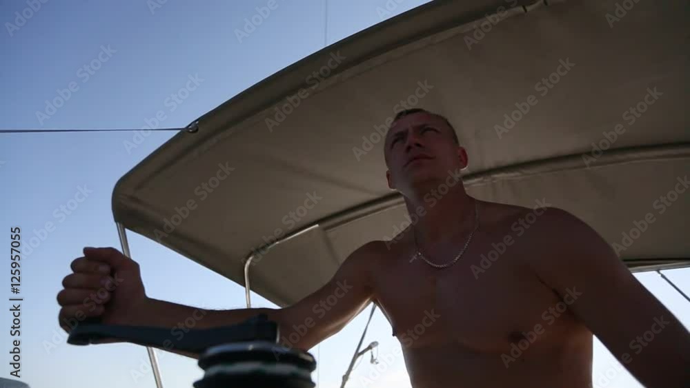 Man Skipper on yacht pulls the rope during drives the sailing boat ...