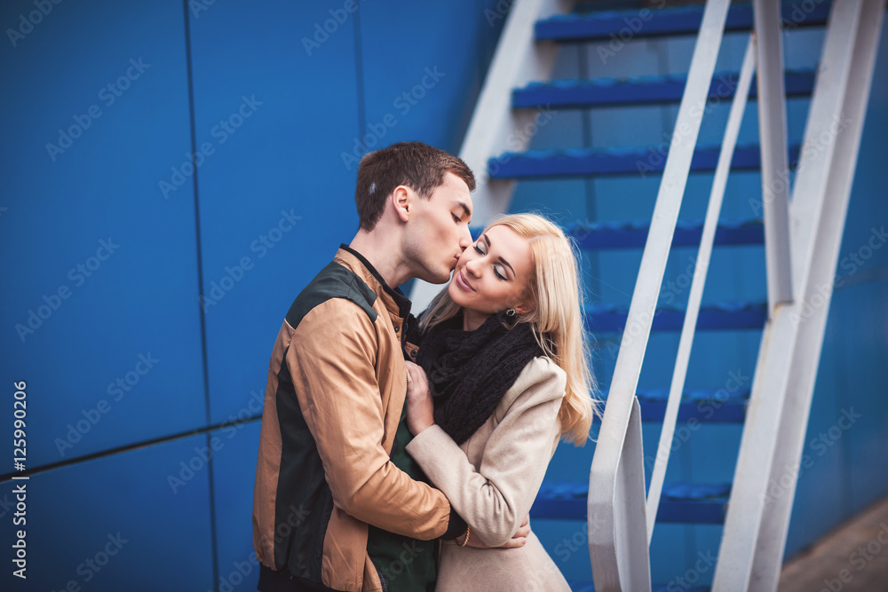 Young couple kissing in blue wall and stairs background. Love concept ...