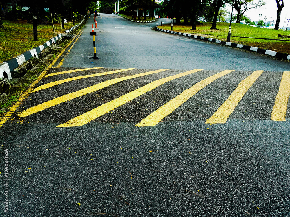 View of yellow stripes road markings to indicate road humps on black ...