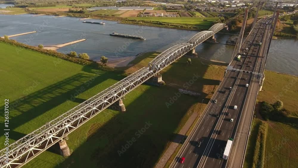 Traffic on bridge over river with transport vessels. A railway bridge ...