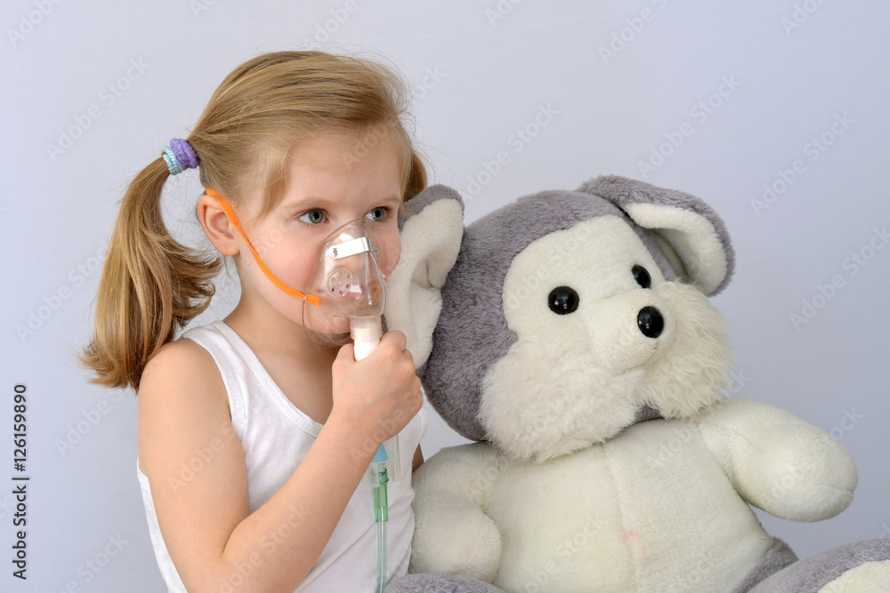 Child, kid (little girl) with inhaler (nebulizer) makes the procedure ...
