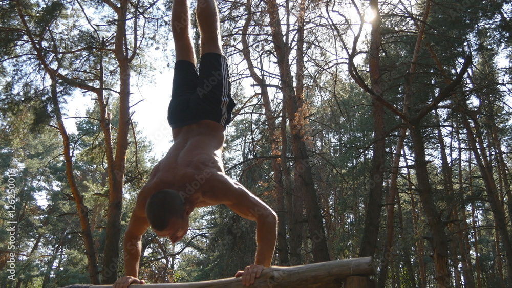 Strong muscular man doing a handstand in a forest. Muscular male ...