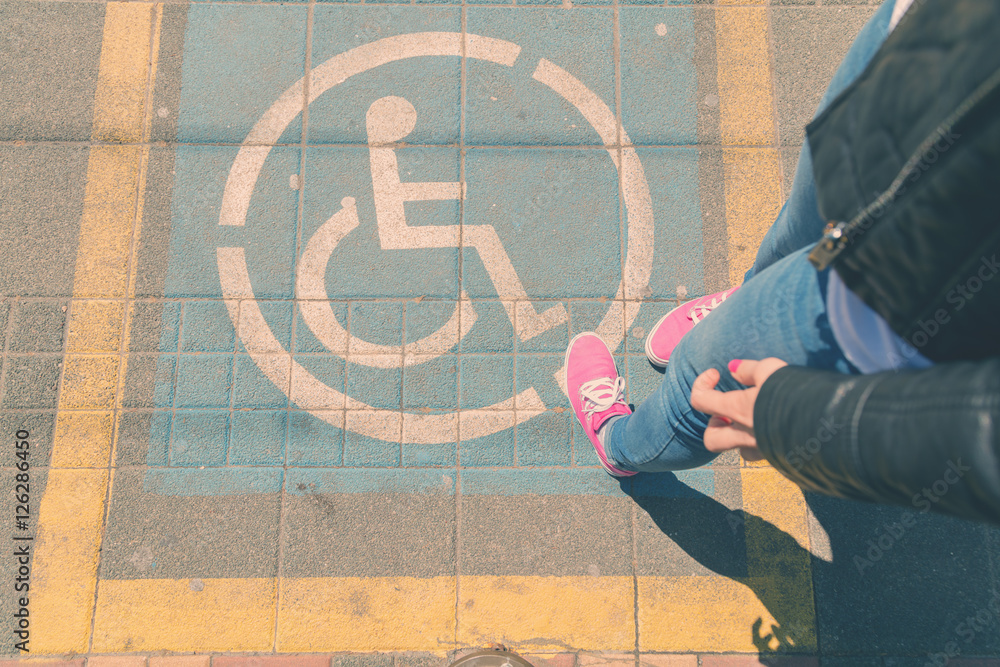 Handicapped person standing on a sign reserved for persons with ...