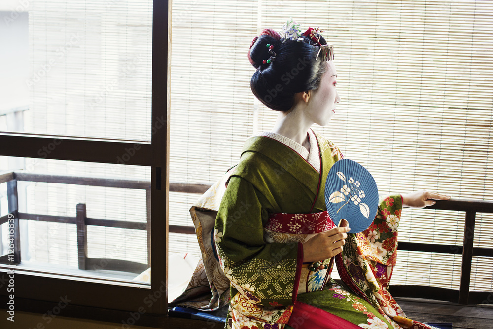 A woman dressed in the traditional geisha style, wearing a kimono and ...