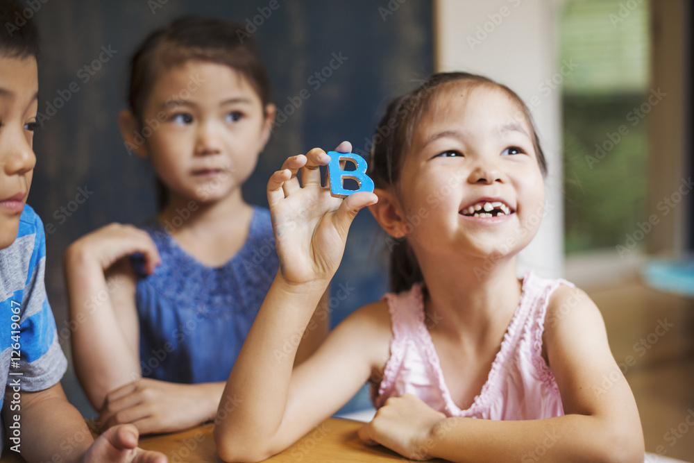 Girl holding up alphabet letter in classroom Stock Photo | Adobe Stock