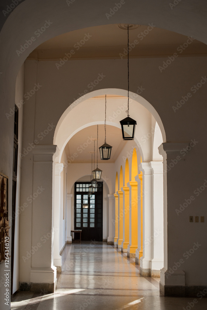 Long white hall consisting of columns and arches. At the end of a ...
