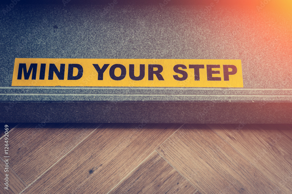 Yellow and black warning sign on stairs stating "Watch your Step Stock ...