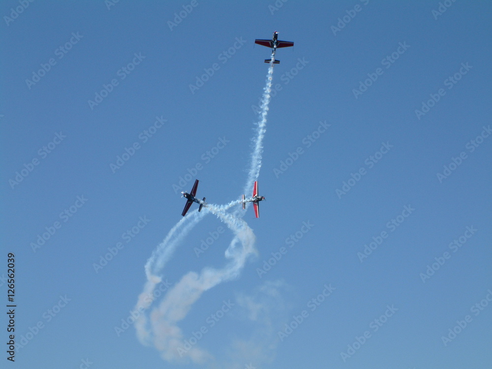 4 small propeller plane in aerobatic display with smoke trails behind ...