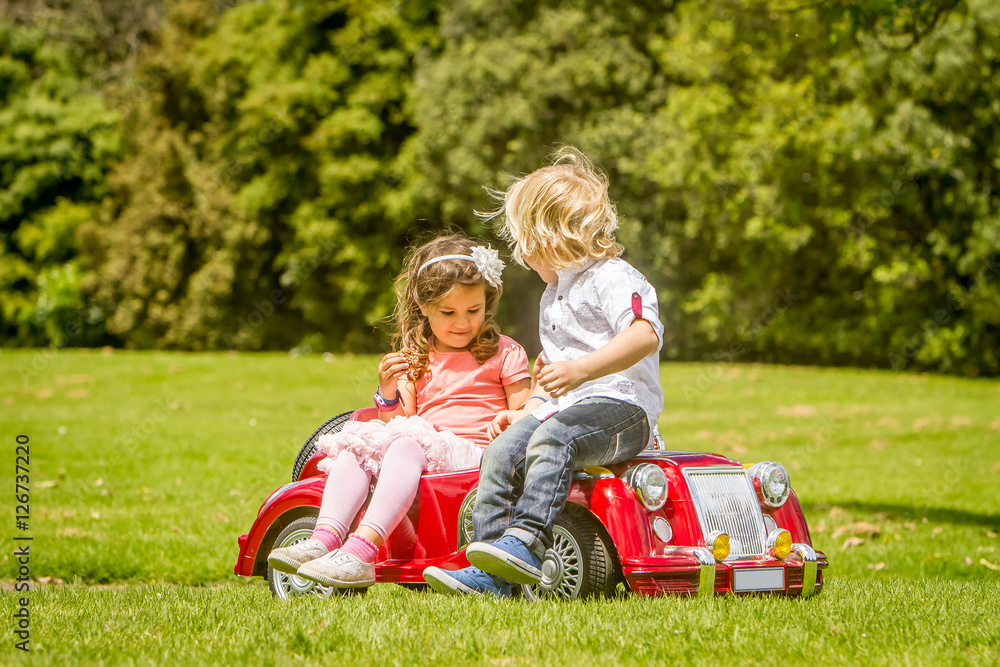young happy children - boy and girl - driving a toy car outdoors Stock ...