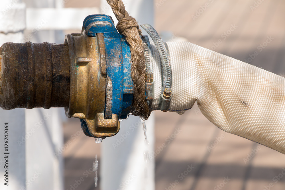 Close, fire hydrant spraying water, connected to hose line. Supply hose ...