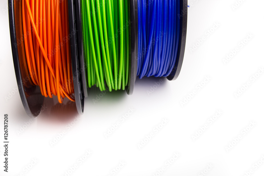 Partial front view of orange, green and blue 3D printer filament spools ...