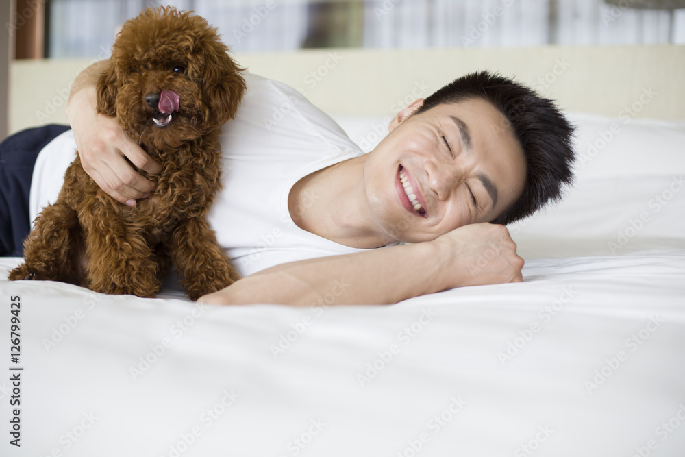 Young man playing with a pet poodle at home Stock-Foto | Adobe Stock