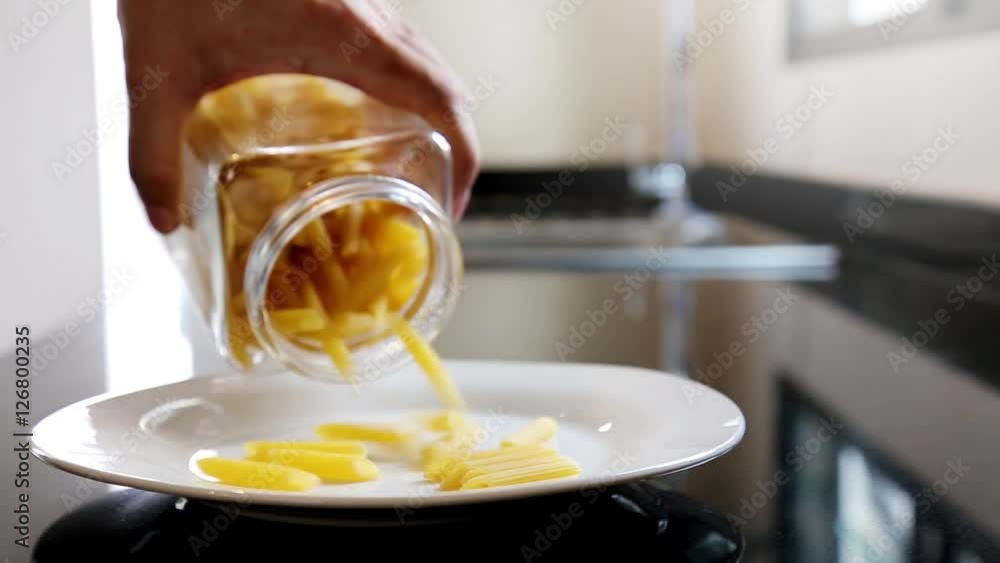 macaroni DROPPING FROM GLASS BOTTLE TI WHITE CERAMIC DISH ON COUNTER ...
