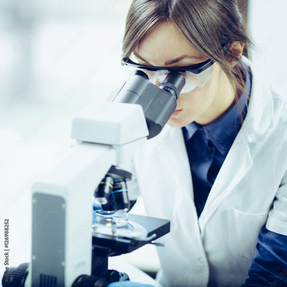 Young scientist looking through a microscope in a laboratory. Young ...