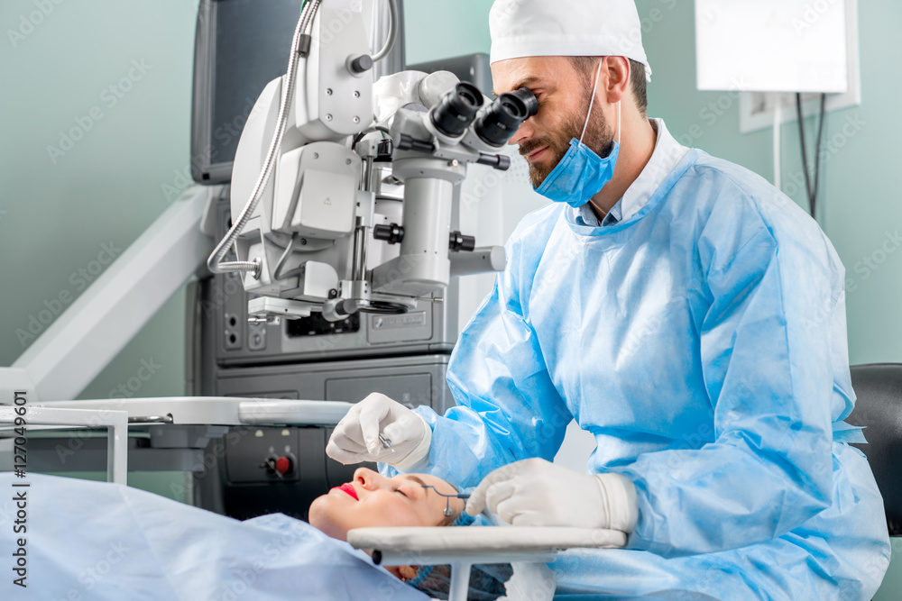 Surgeon operating eye of female patient using surgical microscope at ...