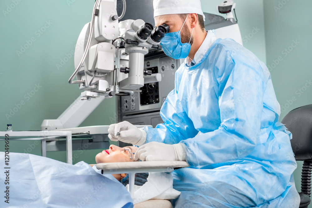 Surgeon operating eye of female patient using surgical microscope at ...