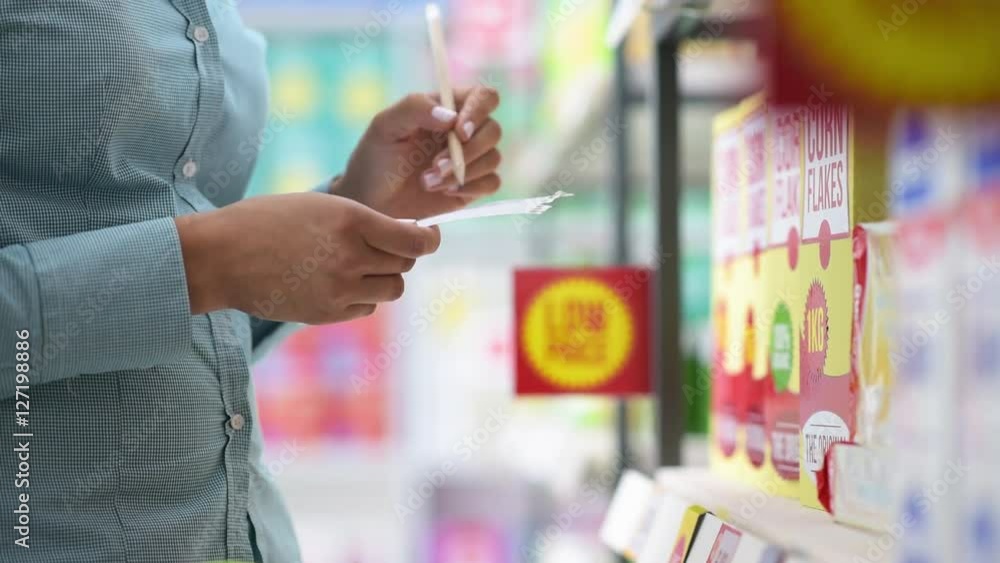 Woman doing grocery shopping at the supermarket, she is checking items ...