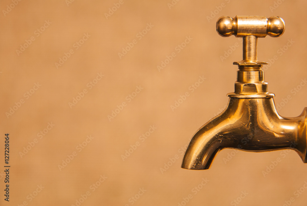 Golden tap on a brown background Stock Photo | Adobe Stock