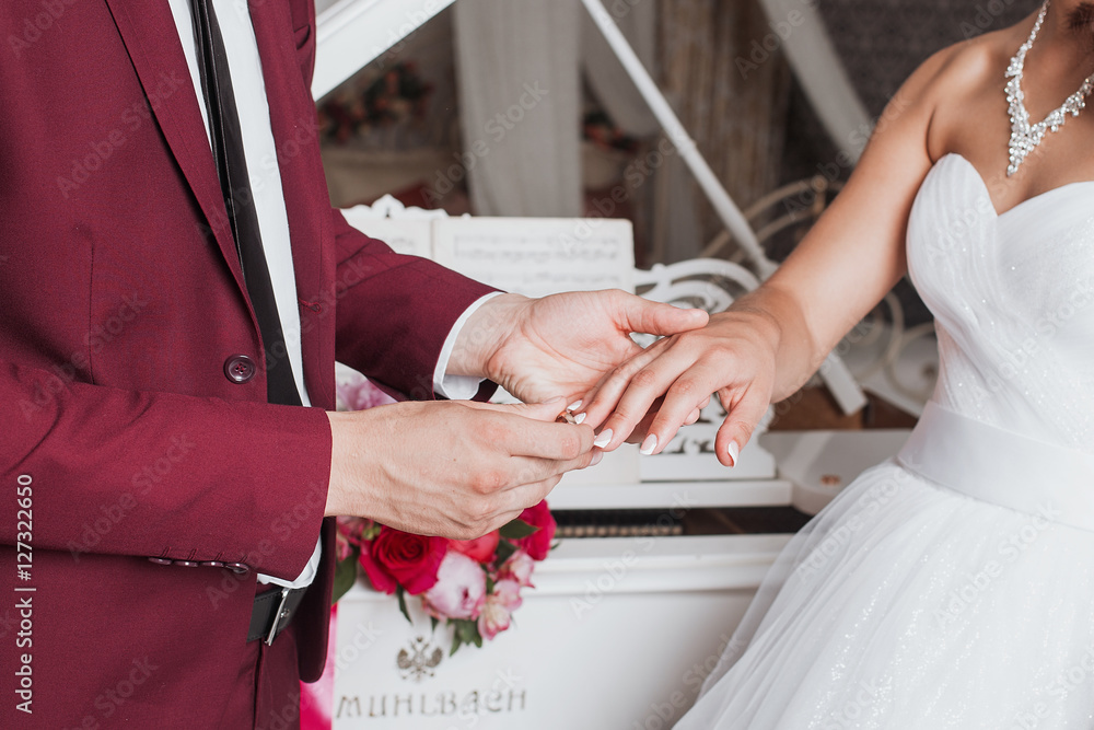 Groom placing a wedding ring on the finger of his bride during ceremony ...