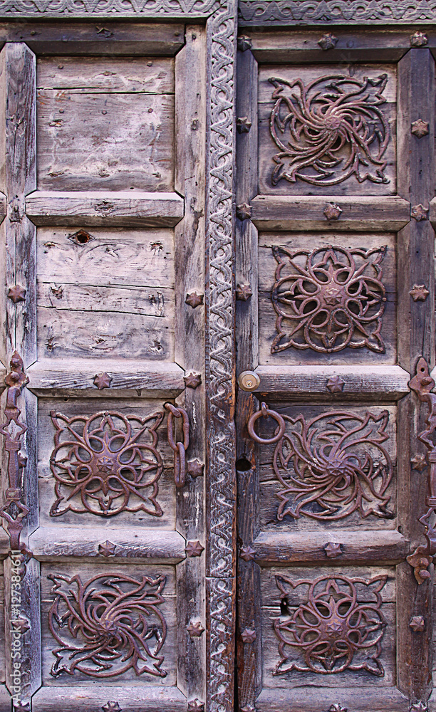Grunge wooden gate background with wrought iron ornaments and carved ...