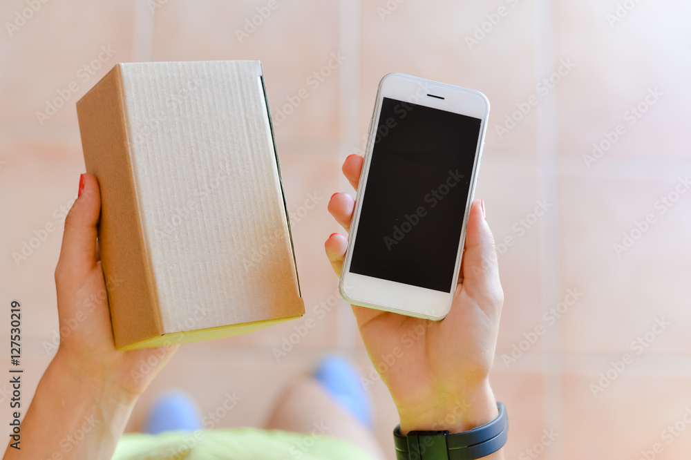 Hand with mobile phone and box on background. Delivery service ...