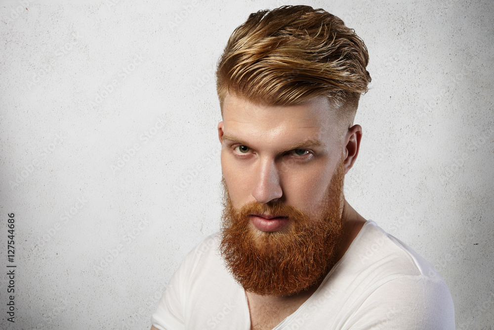 Redhead hipster with trendy haircut and fuzzy beard dressed in white t ...