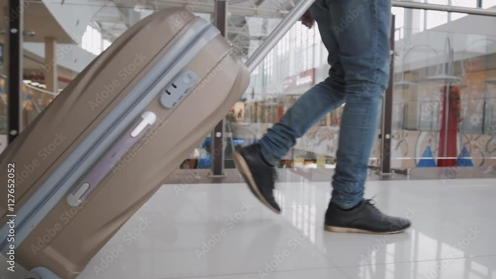 Young man pulling suitcase in modern airport terminal. Travelling guy ...