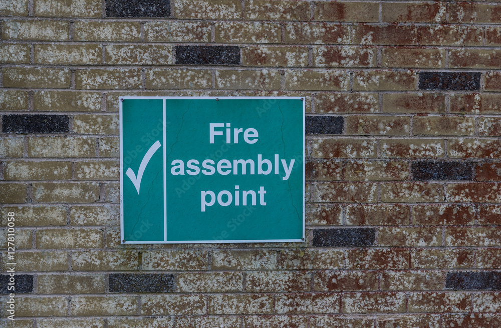 Fire assembly point sign on grunge wall background texture background ...