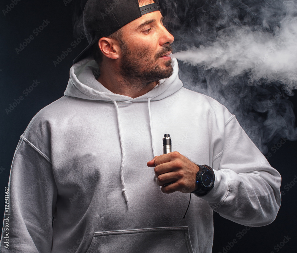 vaping man holding a mod. A cloud of vapor. Black background. Stock ...