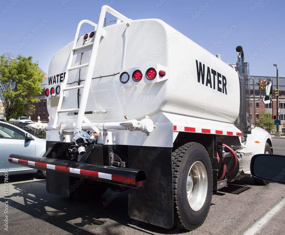 Rear and side view of parked water tanker truck. Blue sky. Horizontal ...