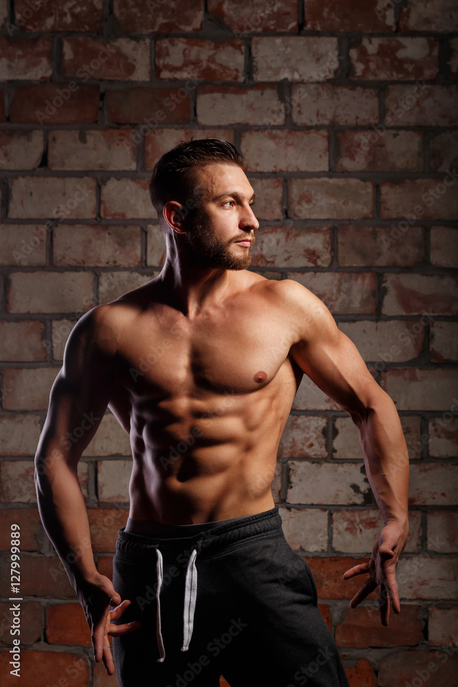 Bodybuilder posing at a brick wall. The athlete ahead of competition ...