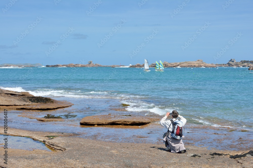 Une randonneuse prend une photo face à la mer à Trégastel en Bretagne ...