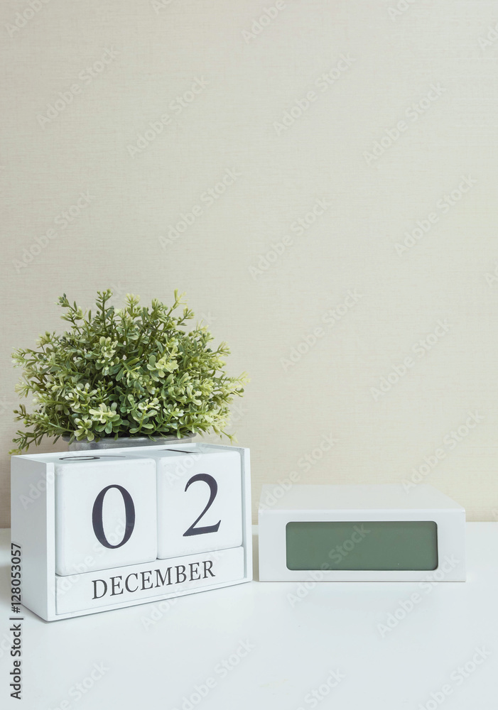 White wooden calendar with black 2 december word with clock and plant ...