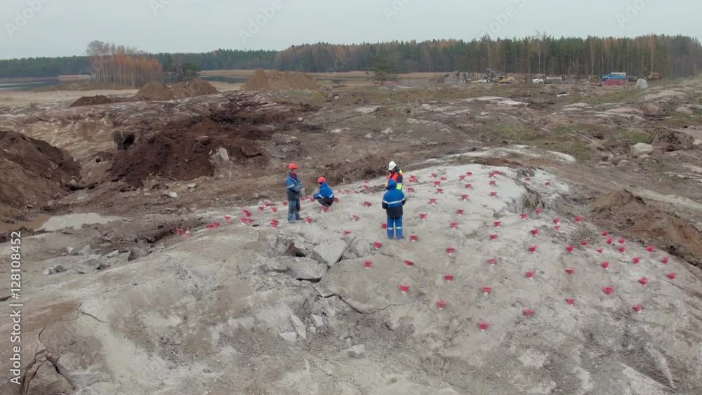 Group of men prepares wires for blasting on construction site ...