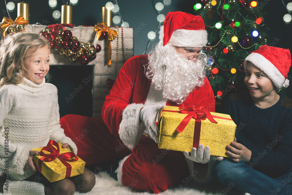 happy Santa Claus and children around the decorated Christmas tree ...