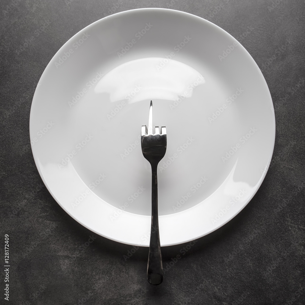Fork bent in the shape of obscene gesture middle finger sign lies on an ...