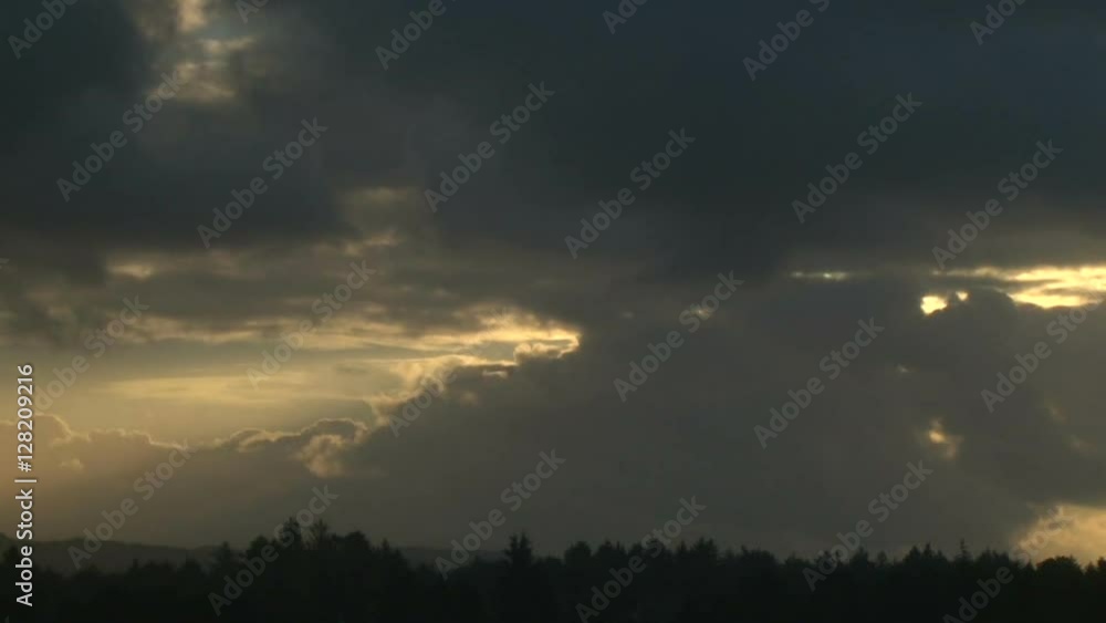 Sunlight shining through heavy rain cloud over trees at sunrise, time ...