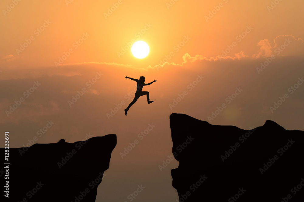 Man jump through the gap between hill.man jumping over cliff on sunset ...