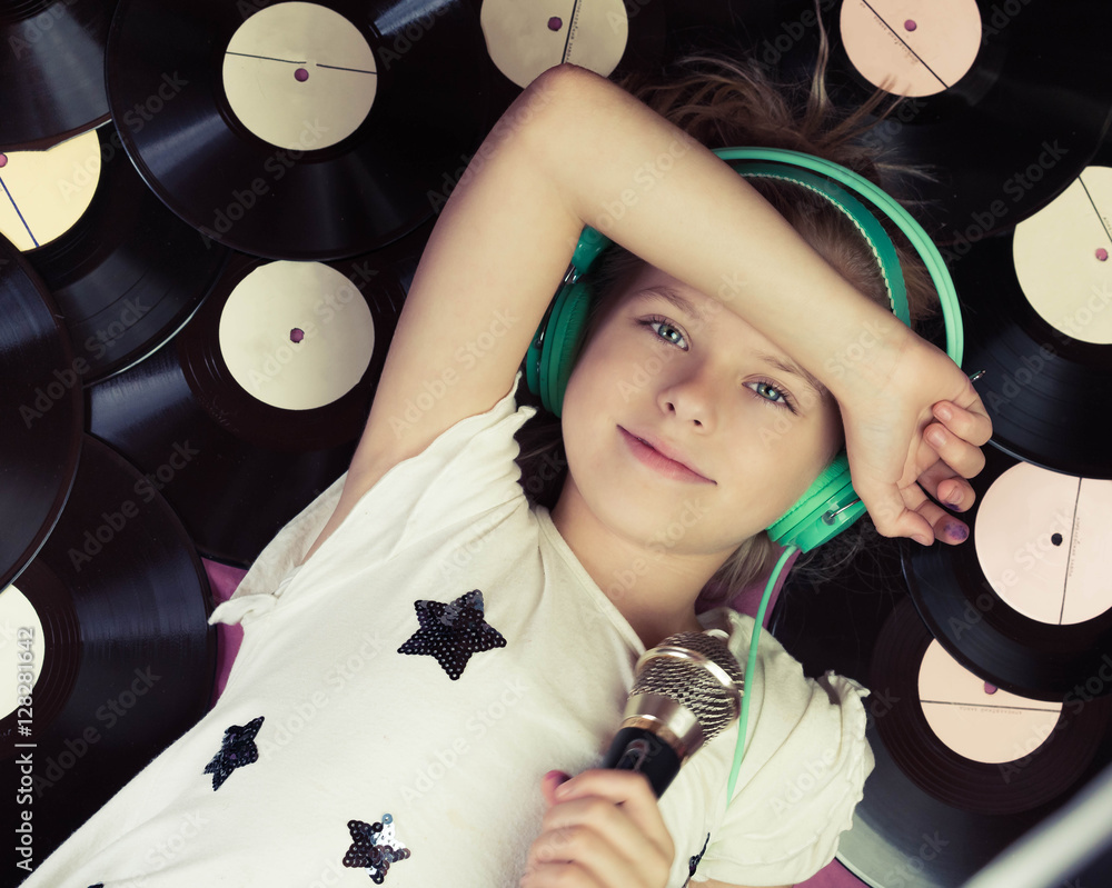 Beautiful girl lying next to vinyl records holding a microphone and ...