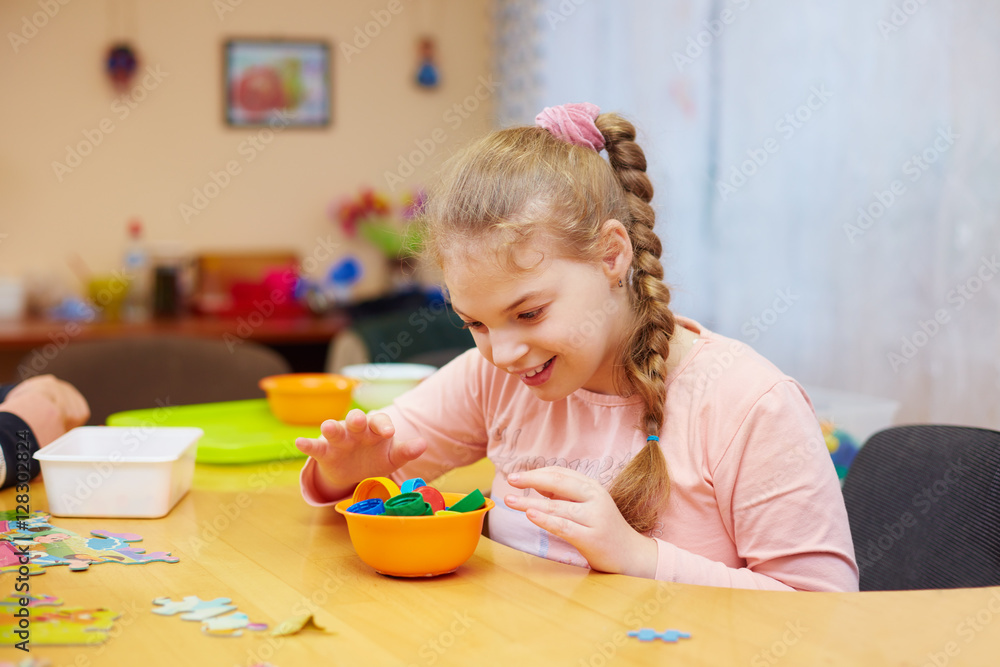 cute happy girl with disability develops the fine motor skills at ...