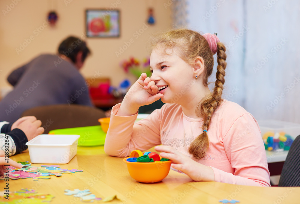 cute happy girl with disability develops the fine motor skills at ...
