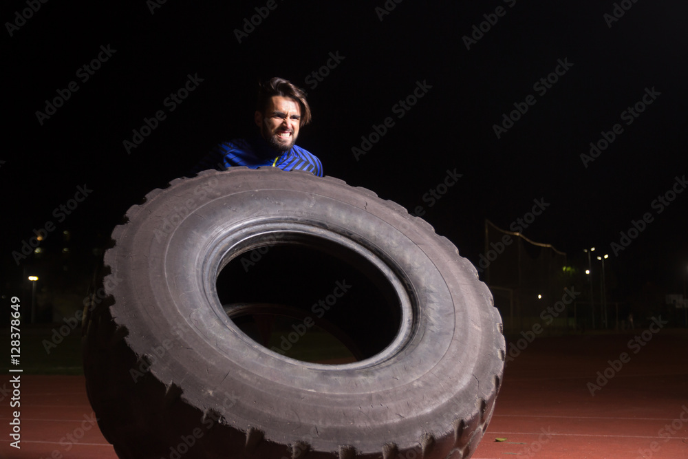 Athlete moving tire exercise, dark, night. Stock Photo | Adobe Stock