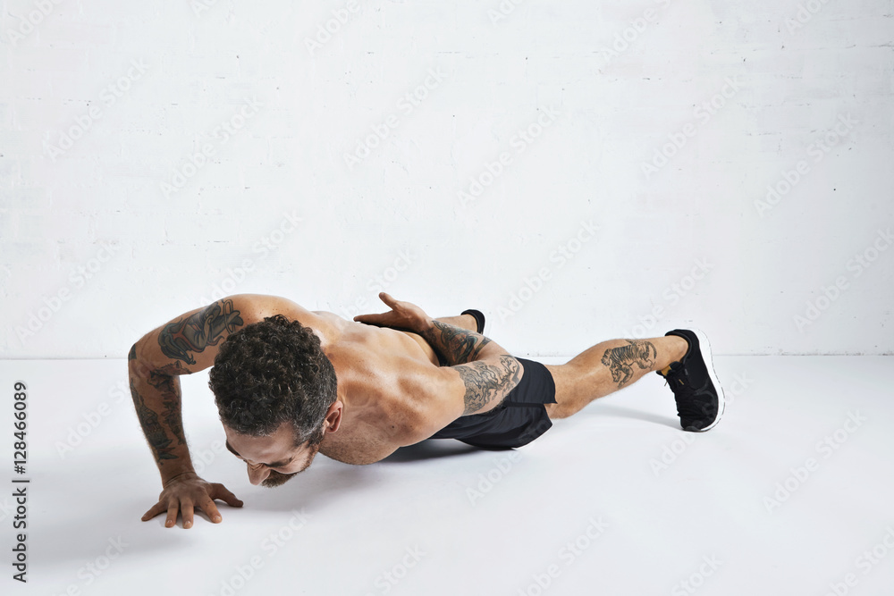Strong brutal tattoed and ripped male athlete shows how to do one hand ...