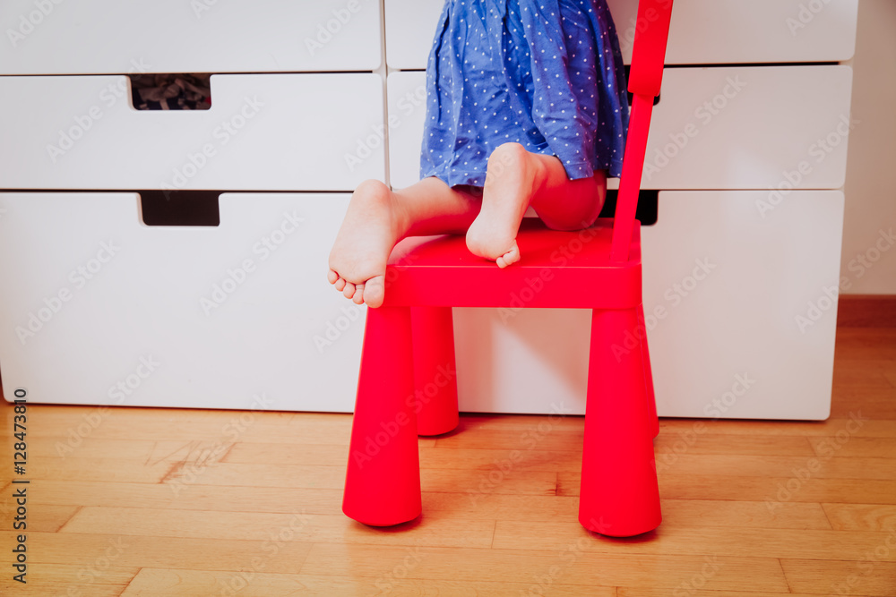 kids safety concept- little girl climbing on baby chair Stock Photo ...