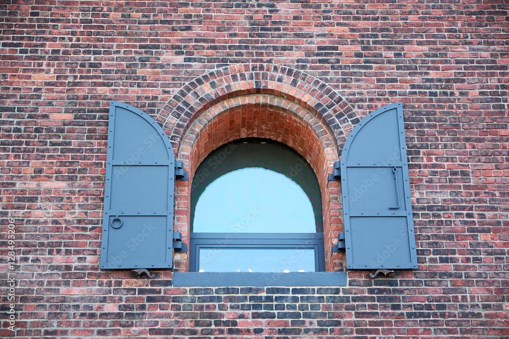 Arched window with belonging shutters on massive hinges, fastened to a ...