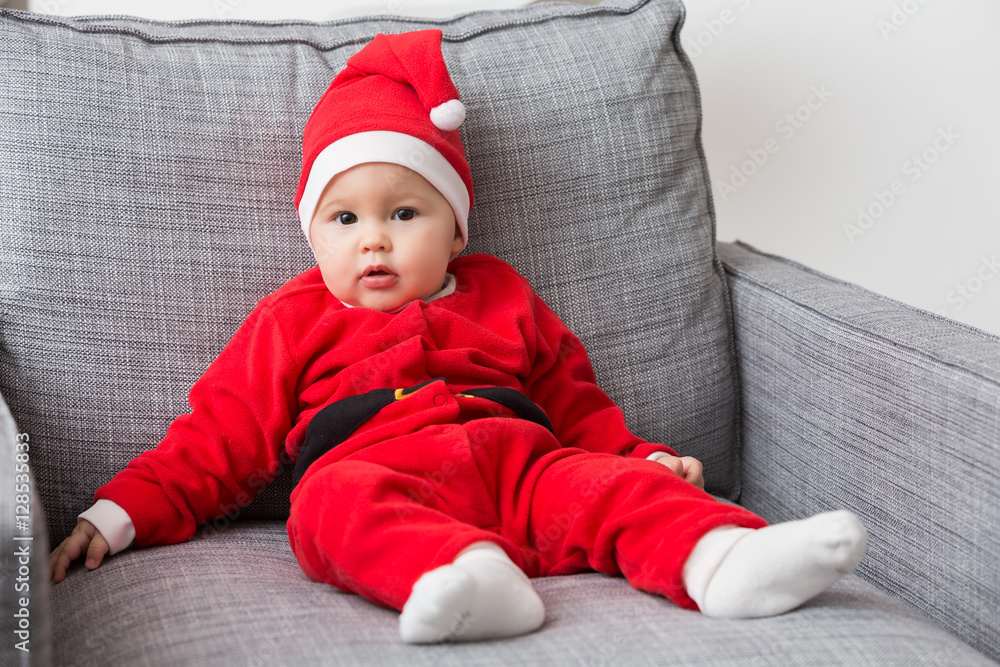 Seven months old baby girl in Santa Claus dress sitting on a sof Stock ...