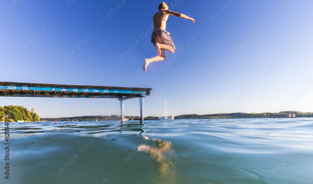 Junge springt vom Steg in den See Stock-Foto | Adobe Stock