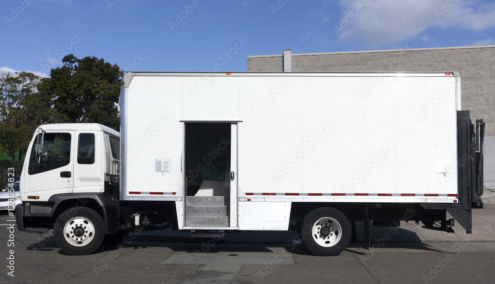 Side view of white delivery truck with side access door open ...